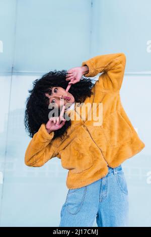 Woman making funny fish faces against a purple background, wearing ...