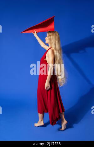 Woman holding a paper airplane and blue sky in the background ...