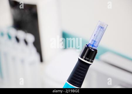 Detail of Derma pen for micro-needling being held by hand wearing blue ...