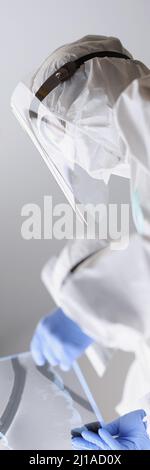 Doctors in protective antiplague suits and screens looking at patient ...