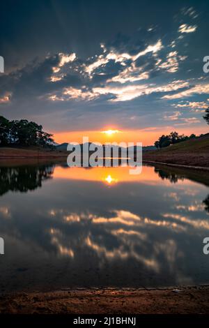 A vertical shot of a beautiful sunset reflecting on the surface of the ...