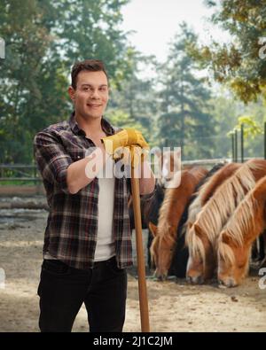 Portrait of cheerful man horse farm worker standing at stable Stock ...