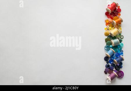 A lot of buttons and reels with colorful threads, laid out on a white ...