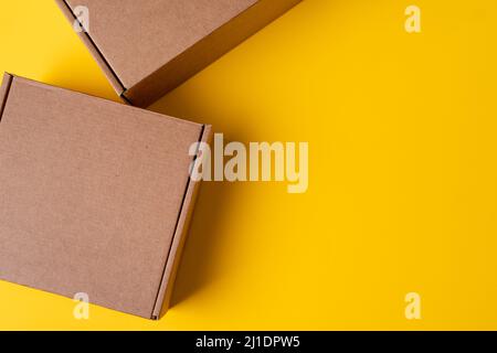 Beige cardboard boxes on yellow background, close up Stock Photo - Alamy