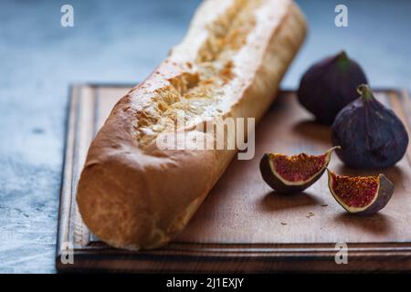 Fresh baguette with crispy crust and fruits of ripe figs on the table ...