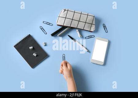 Child's hand with mobile phone and stationery on grey background Stock ...