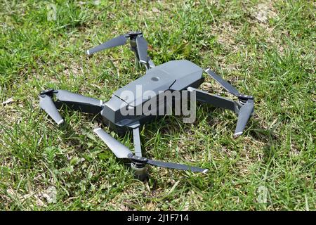 Mini drone unfolded on a grass before take-off. Small drone flies in ...