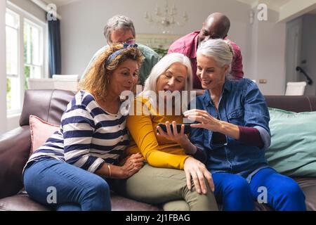Surprised multiracial senior female friends looking at smart phone ...