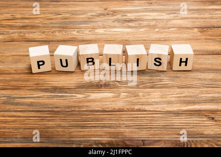 row of wooden cubes with publish lettering on brown textured surface ...