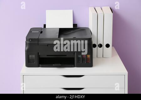 Chest of drawers with printer and folders near color wall Stock Photo ...