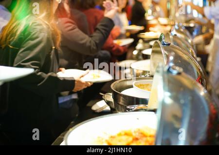 Group of people grab some buffet self service food on their own plate ...