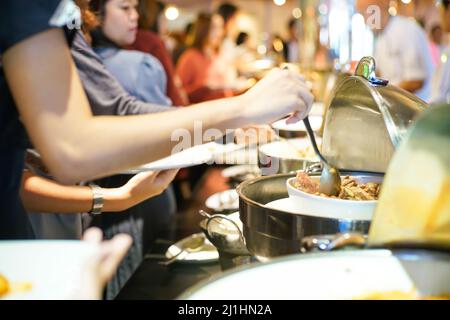 Group of people grab some buffet self service food on their own plate ...