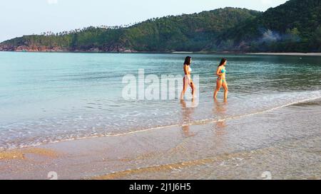 A distant shot of two females walking at the beach in Koh Samui ...