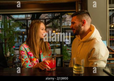 amazing and attractive young couple is talking and drinking while ...