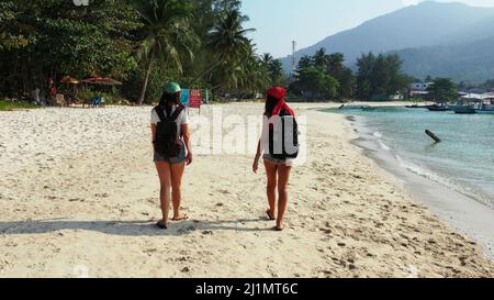 A backshot of two Caucasian females with backpacks walking on the ...