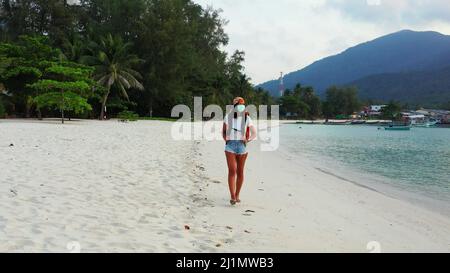 A Caucasian female with a backpack and face mask walking on the ...