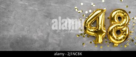 Gold foil balloon number number 48 on a background of black tinsel ...