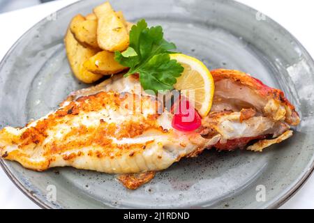 plate of grilled red scorpion fish fillet and vegetables on restaurant ...