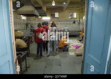 A group of tourists and locals with a Sikh man cooking at the free ...