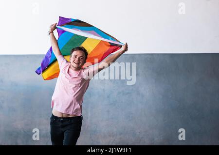 Cheerful transgender person jumping in front of rainbow wall Stock ...