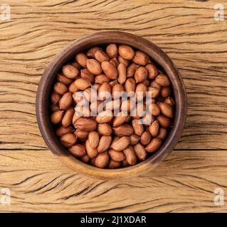 Peanuts in a bowl over wooden table Stock Photo - Alamy