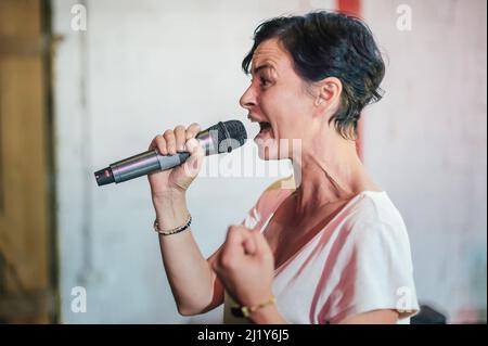 Smiling and witty female stand up actor comedian on stage, talking and ...
