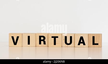 The word VIRTUAL is written on a wooden block on a computer keyboard ...