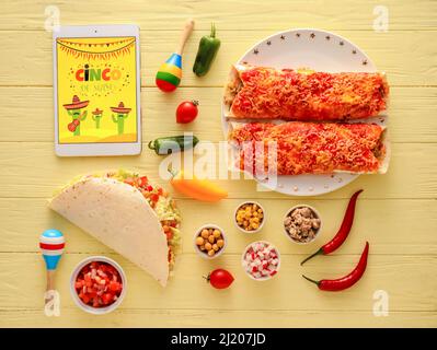 Traditional Mexican food with maracas and tablet computer on color ...