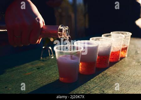 Plastic glasses with pink champagne. Nature picnic concept. Front view ...