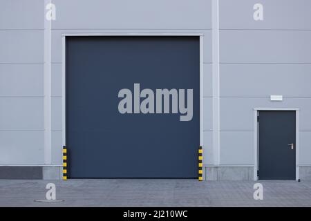 facade of industrial storehouse with closed gray metal gate and door ...