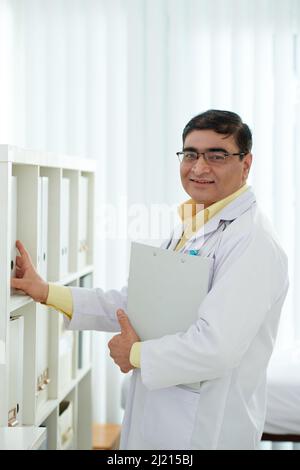 Doctor taking patient history from older woman at a desk in a clinic ...