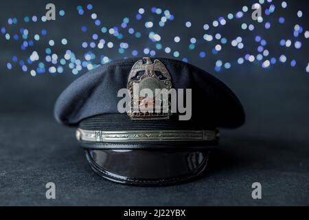 A navy blue police hat cap in front of a navy blue background with copy ...