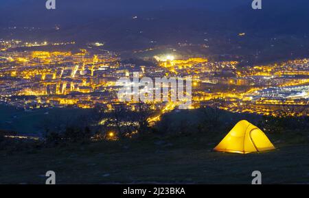 camping tent at night with the lights of the city in the background ...
