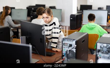 Teen schoolgirl learning basics of programming in computer college ...