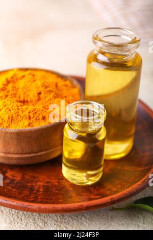 Bottles of essential turmeric oil, powder and root on white background ...