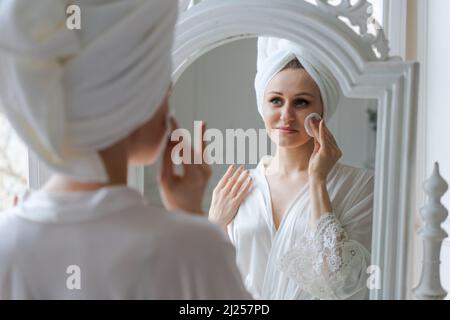 Woman removing makeup, holds cotton pads near face. Photo of woman with ...
