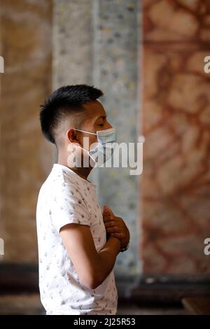 Faithful wearing a face mask and praying in Sagrario catholic church ...