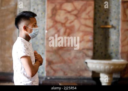 Faithful wearing a face mask and praying in Sagrario catholic church ...