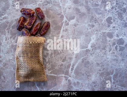Poured dates top view. Dried date fruits in sack bag on marble ...