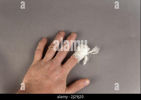 The hand of a mature man with a bandaged index finger. The man holds ...