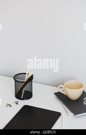 Notebook, holder with stationery, cup of coffee and pine cones on ...