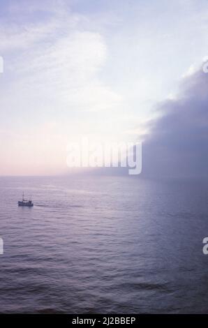 Fishing boat dominated by huge squall cloud at sea, Sep 1979 Stock ...