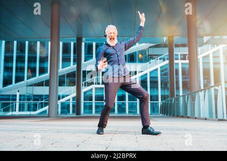 Energetic businessman dances and listens to music Stock Photo - Alamy
