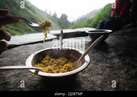 instant noodles like maggi served in steel plate bowl with forks staple ...