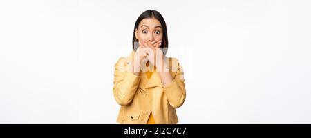 Image of shocked asian girl shuts mouth, close lips and looking ...