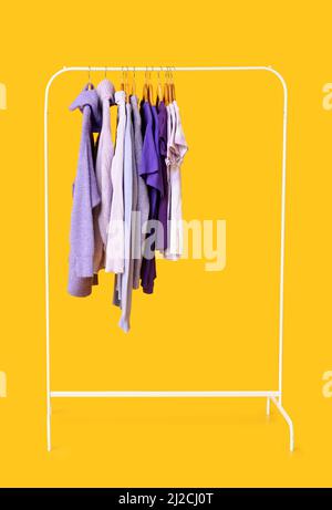 Rack with clothes in purple shades on lilac background, closeup Stock ...