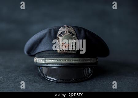 A navy blue police hat cap in front of a navy blue background with ...