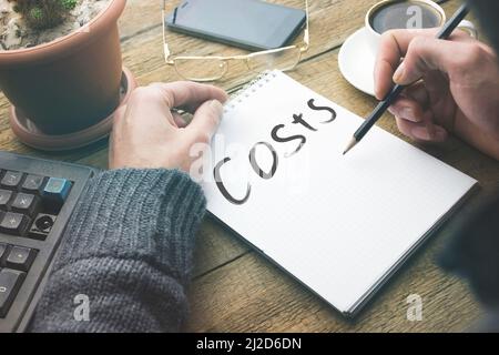 costs text on notebook on working table Stock Photo - Alamy
