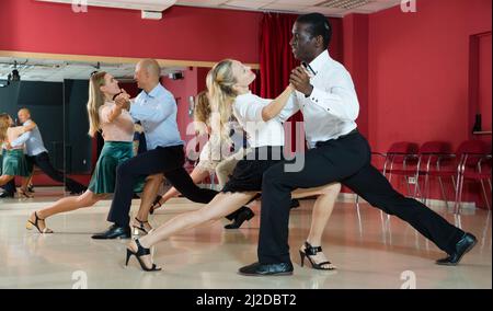 Adult pairs dancing tango movements in modern dance studio Stock Photo ...