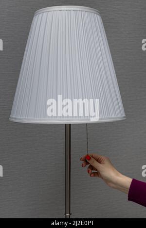 woman pulling the switch chain of a floor glowing lamp. High quality ...